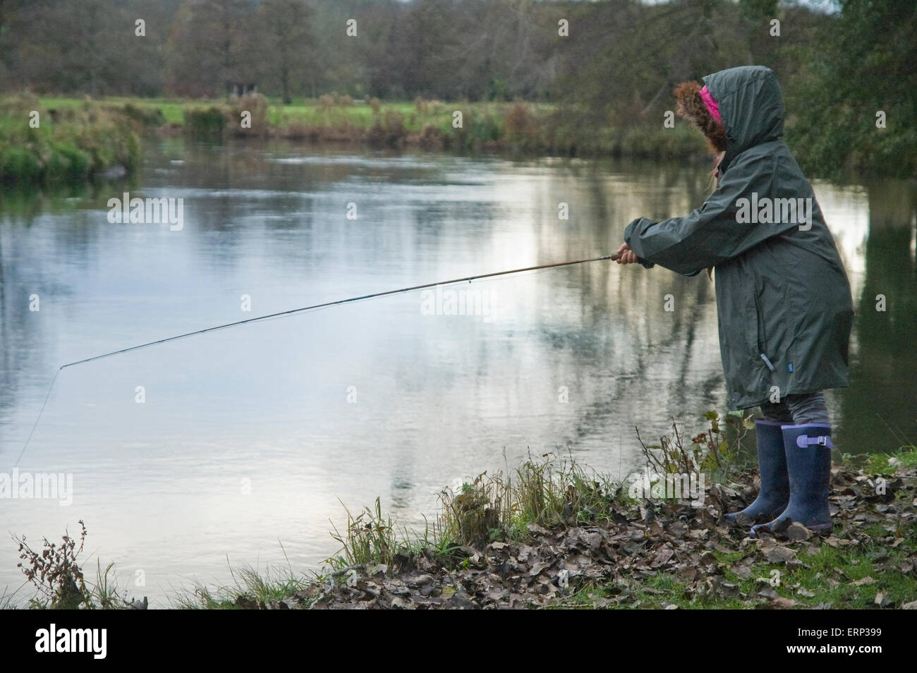 A young fisher girl tries to catch a fish on an english chalkstream ...