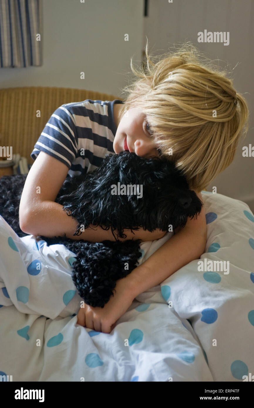 A little blond boy hugs his pet cockapoo Stock Photo - Alamy