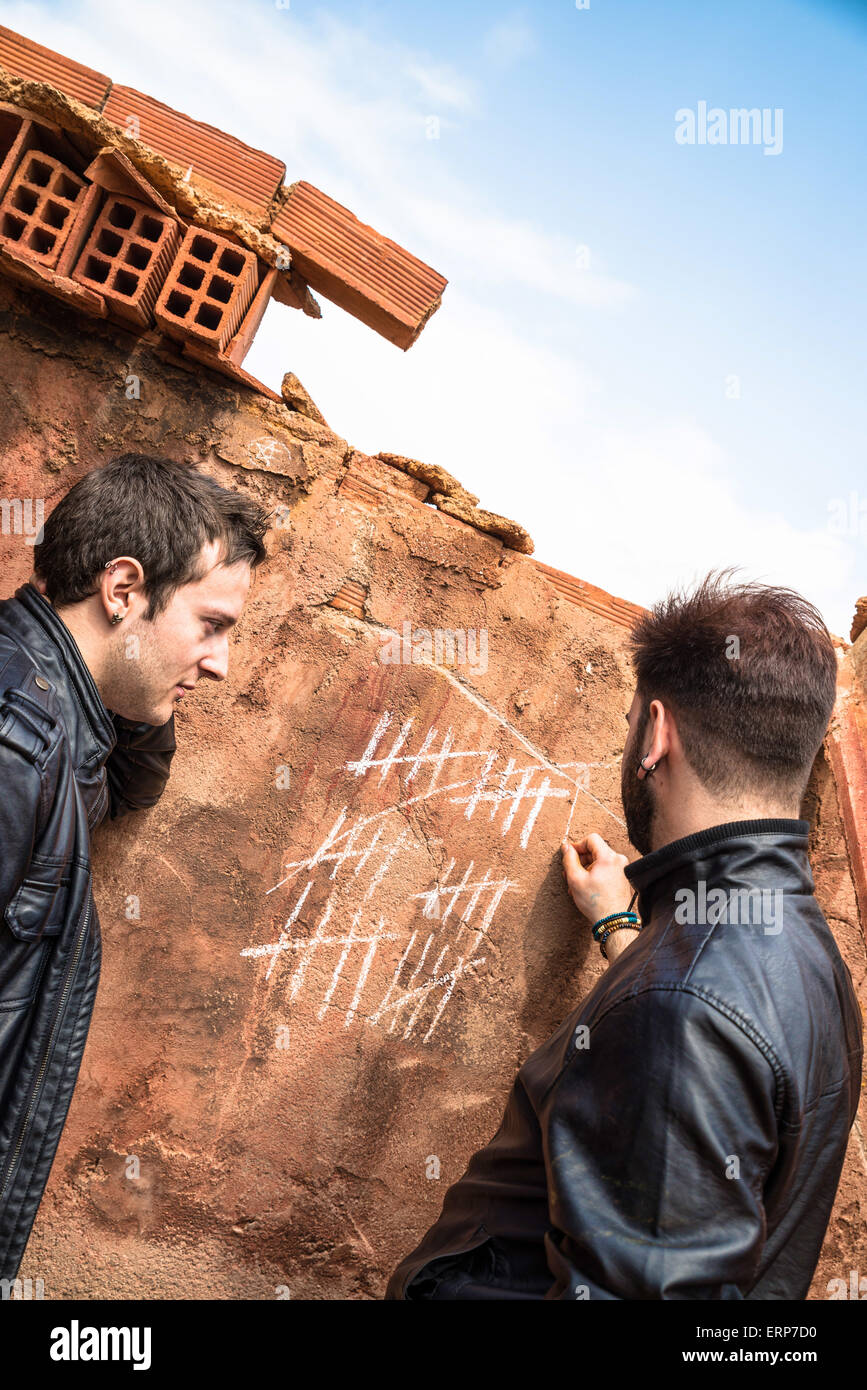 Two guys counting days with chalk markings on a wall Stock Photo - Alamy