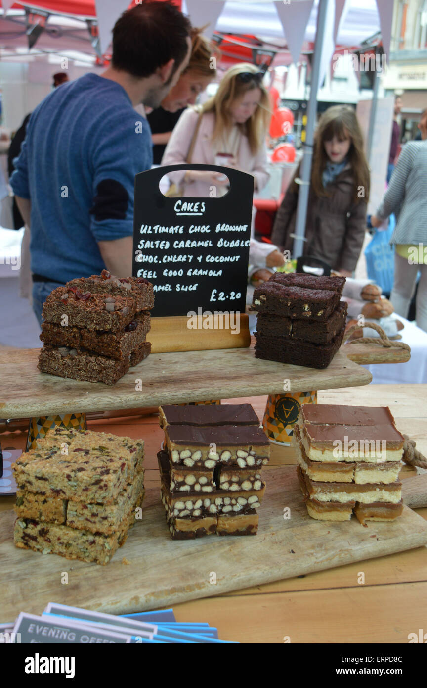 a market stall selling cakes with customers in the background, Vivienne ...