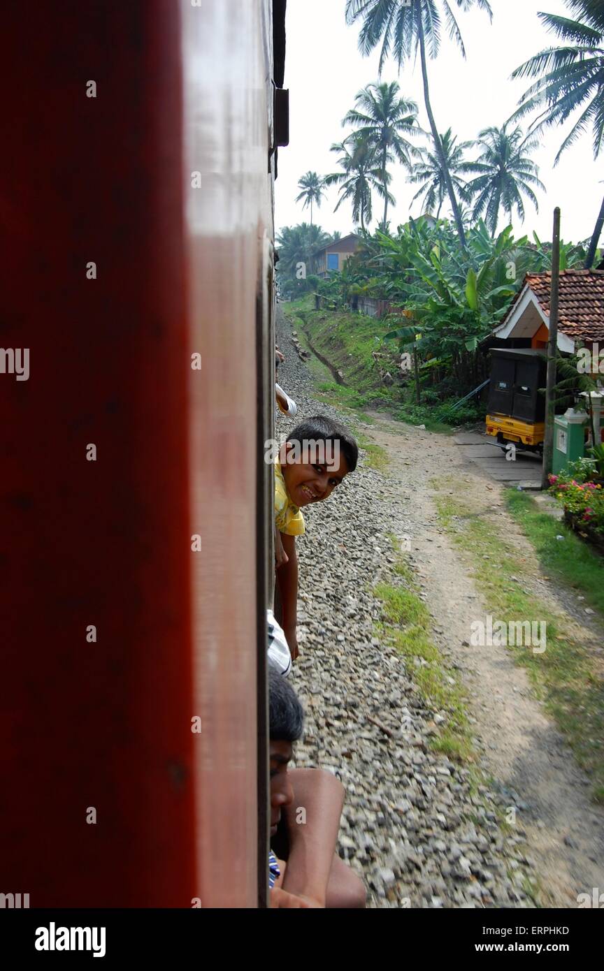 A boy smiling at the camera whilst leaning out of the window of a train ...