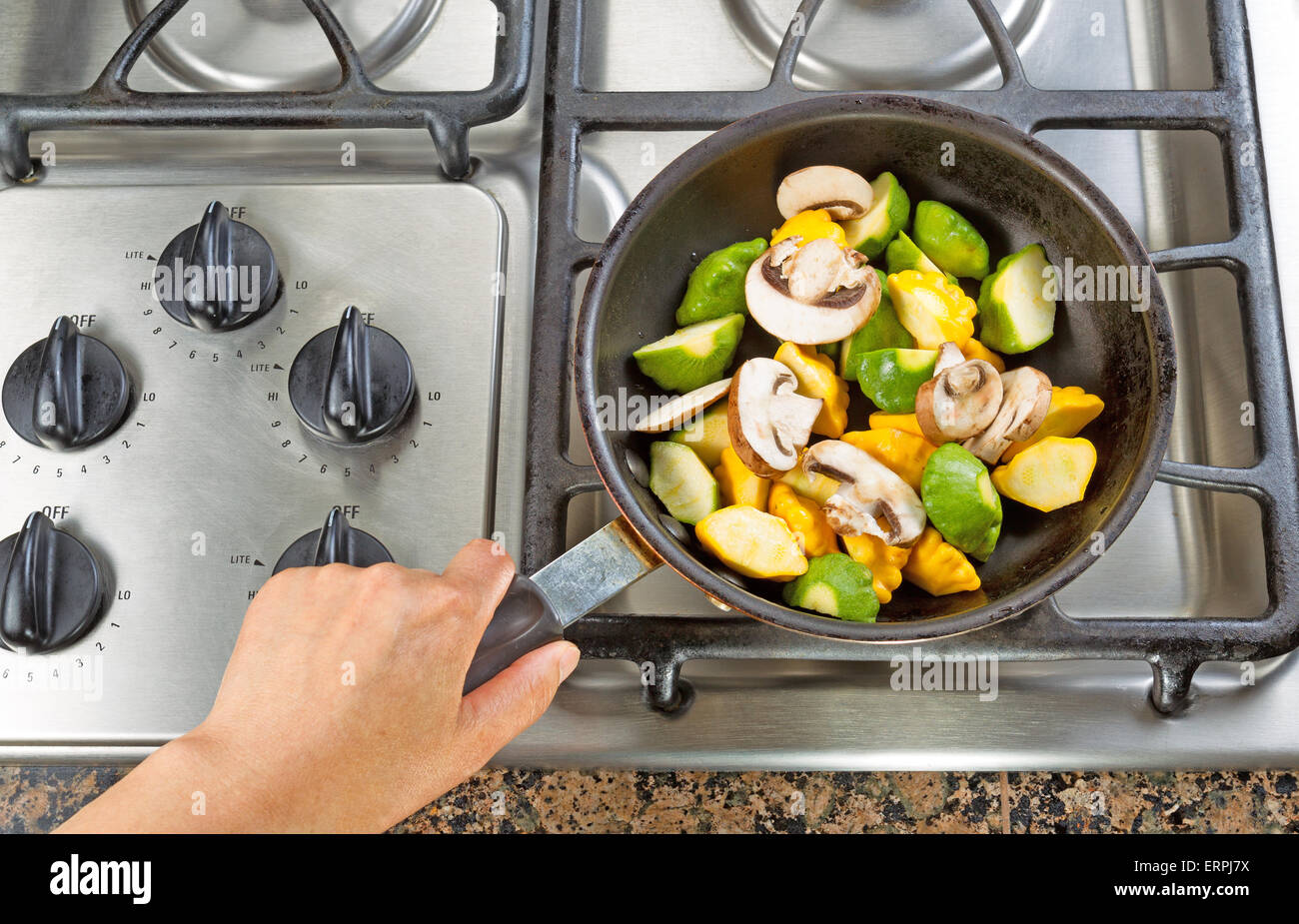 High angle view of hand holding frying pan while cooking vegetable in ...