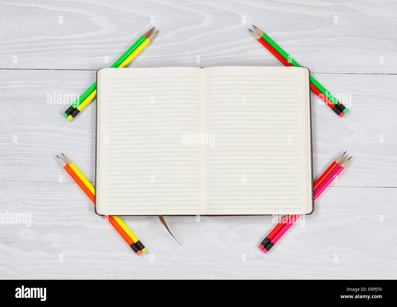 High angled view of open notebook with newly sharpen pencils placed at ...