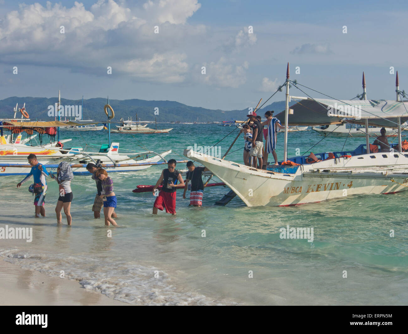 Tourists boarding a traditional panga boat in Boracay, Philippines ...