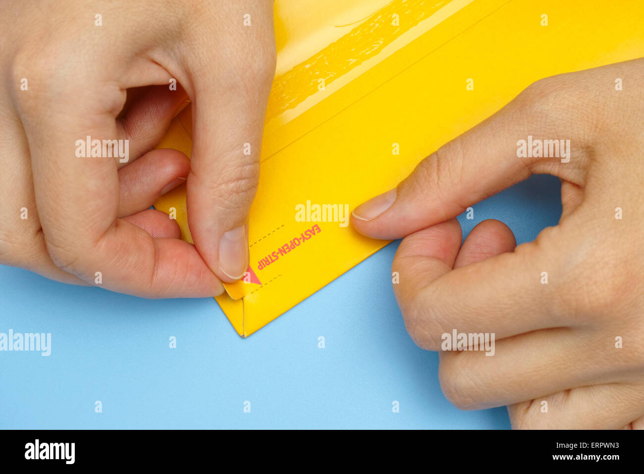 Woman hands opening mail package with easy open strip Stock Photo - Alamy