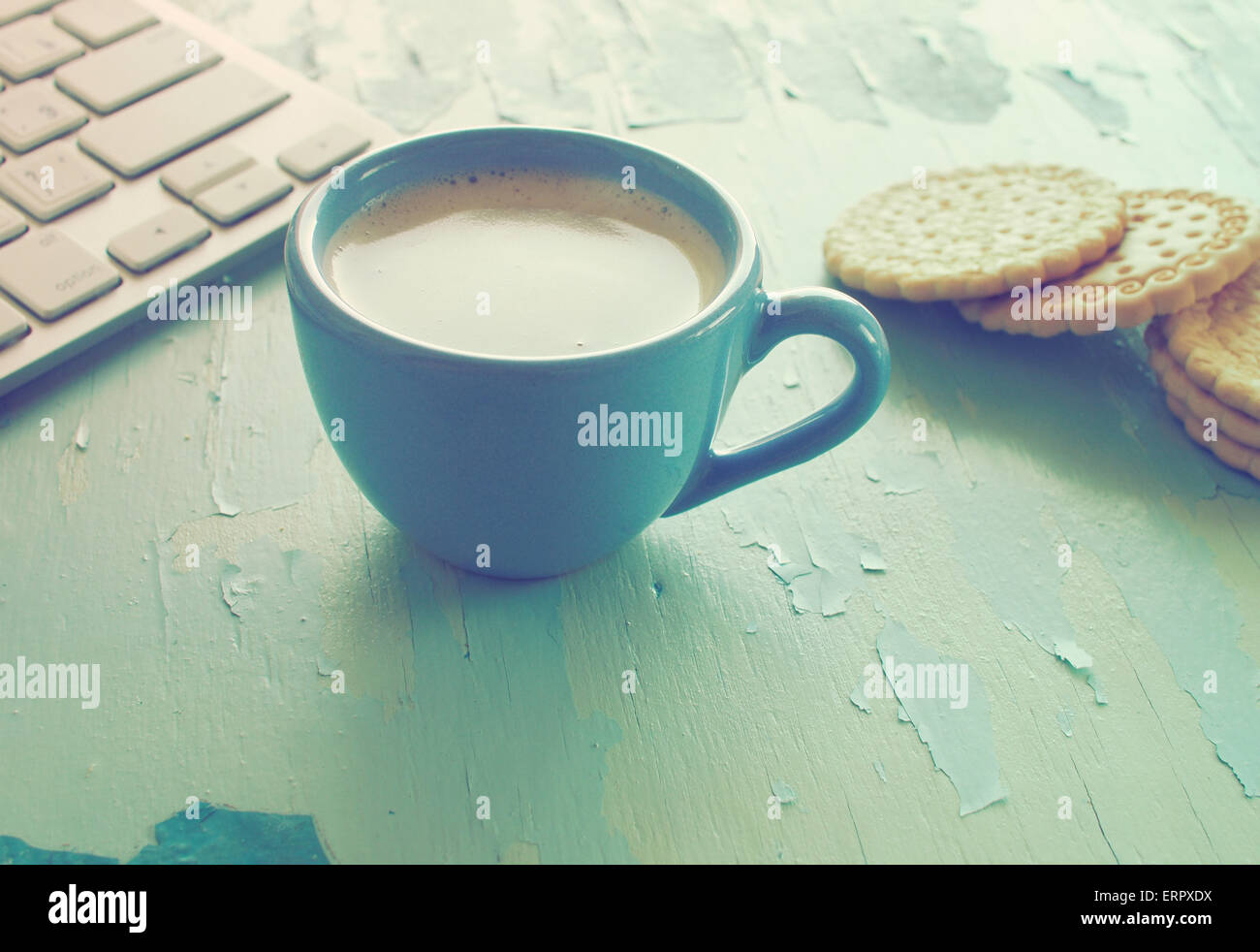 Computer keyboard, cup of coffee and biscuits on blue painted ...