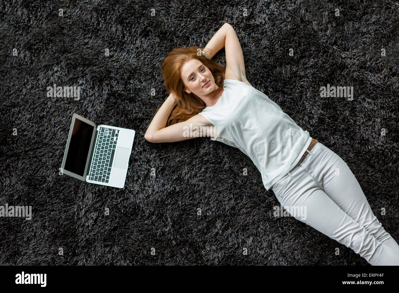 Young woman laying on the carpet Stock Photo - Alamy