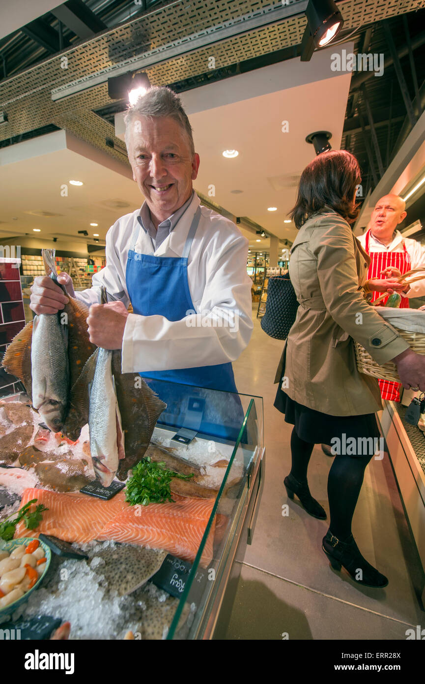 A fishmonger at his counter holding Plaice and Sea Bass UK Stock Photo ...