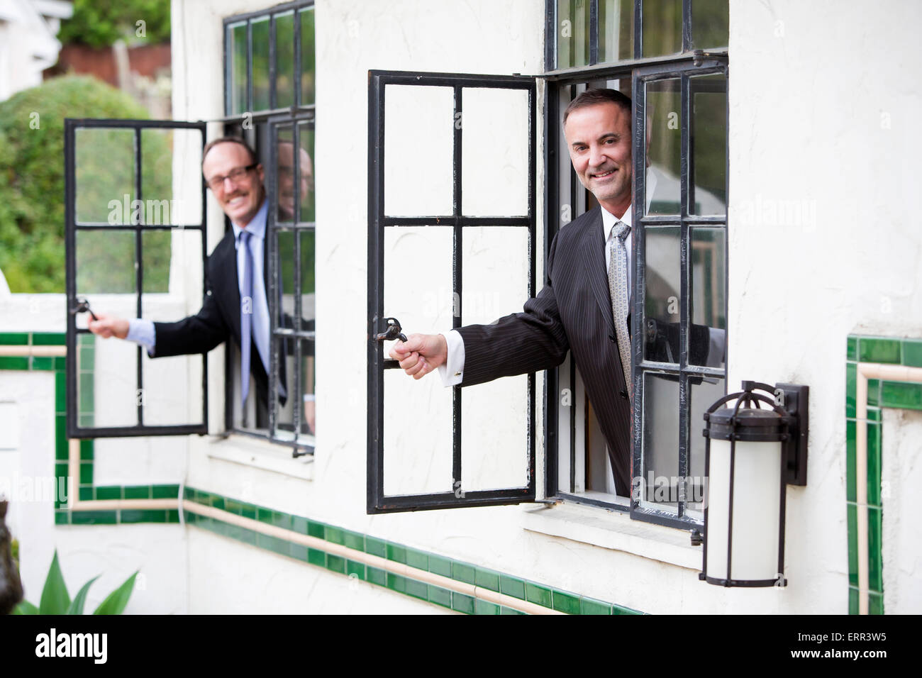 two businessmen looking out of a window and smiling Stock Photo - Alamy