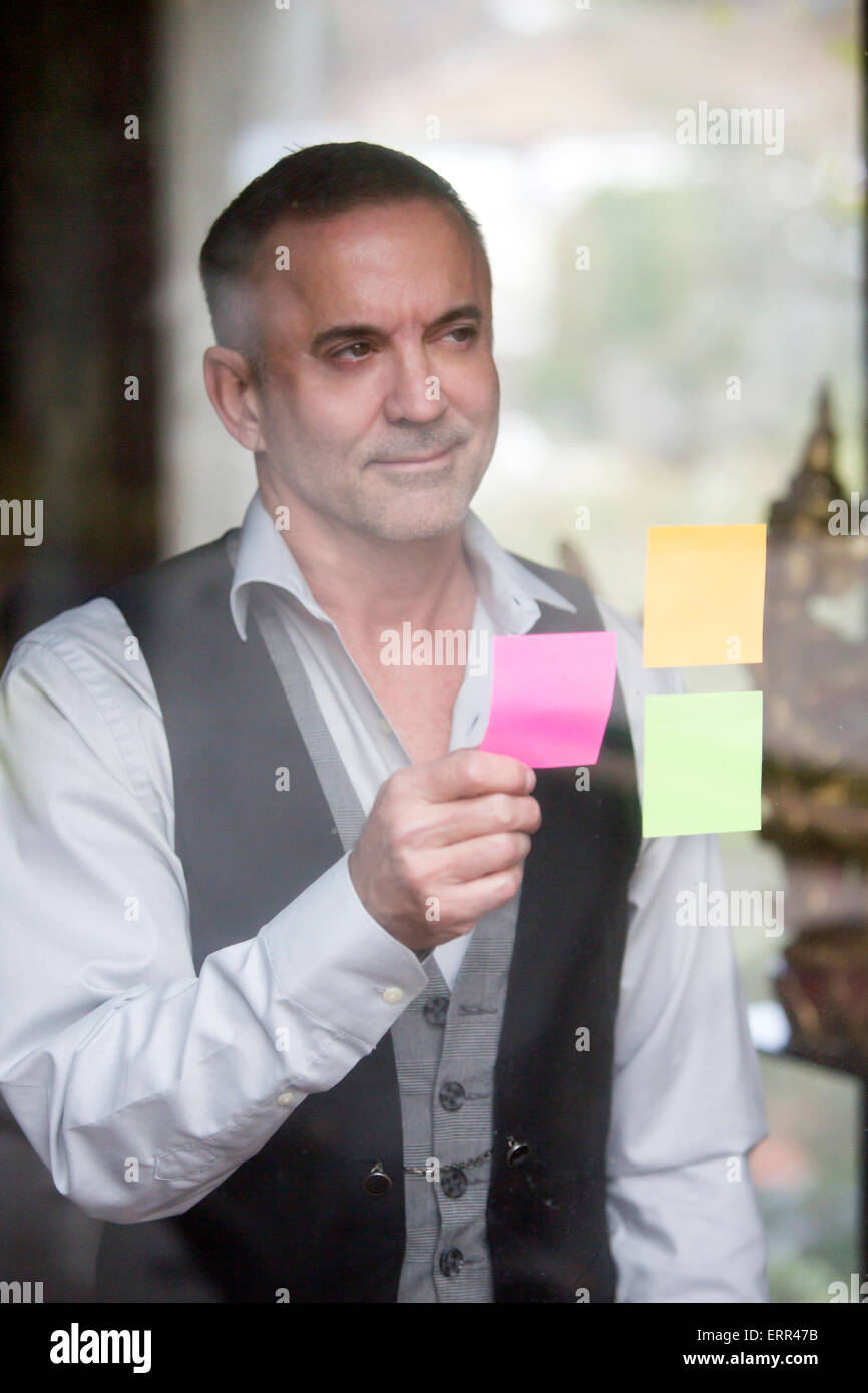 businessman by the window looking at notes Stock Photo - Alamy