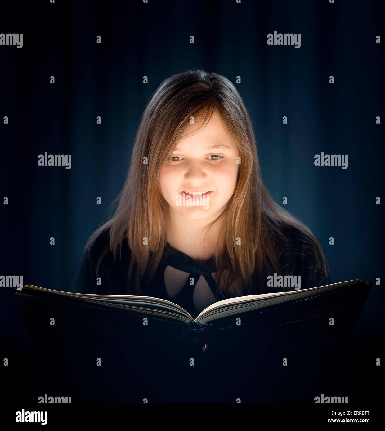 Young girl with long hair reading a book with glowing light Stock Photo ...