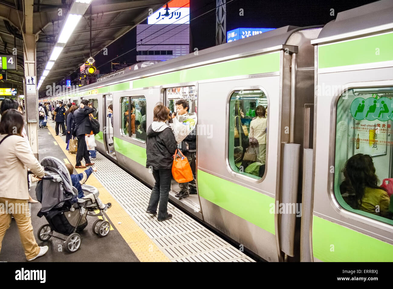 Platform of a Tokyo loop line station with commuters getting on and off ...
