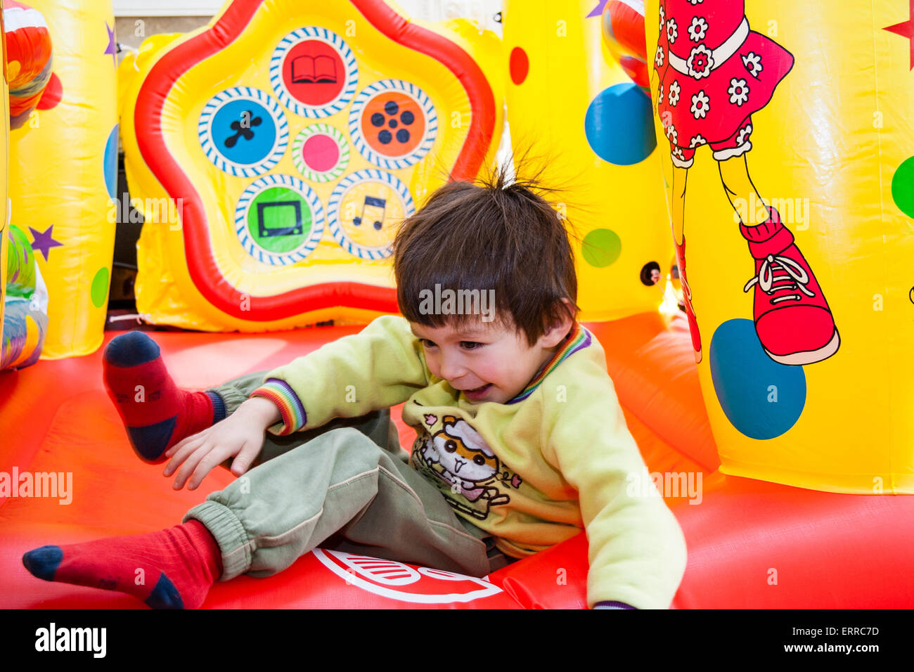 Caucasian child, boy, 4-5 year old, playing indoors on a bright red and ...