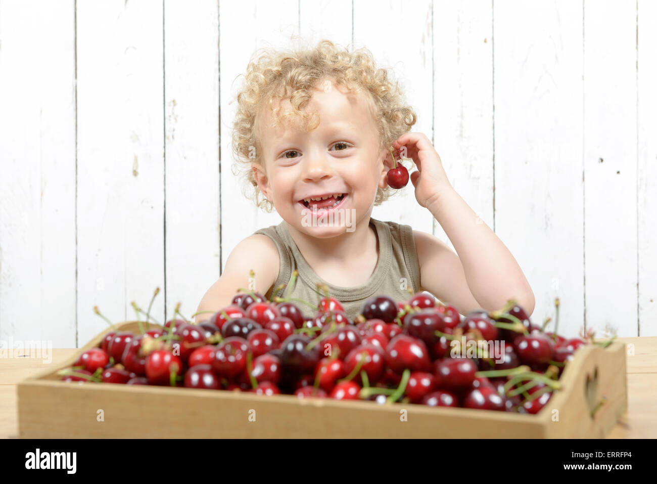 a little blond boy playing with cherries Stock Photo - Alamy
