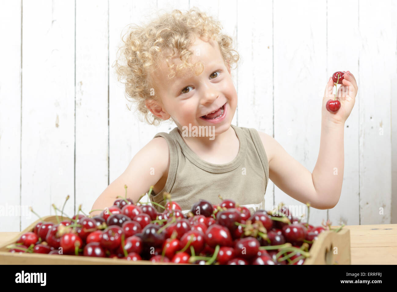 a little blond boy playing with cherries Stock Photo - Alamy