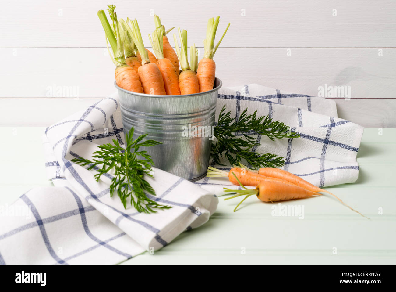 Carrots inside metal bucket on the light green wooden table Stock Photo ...