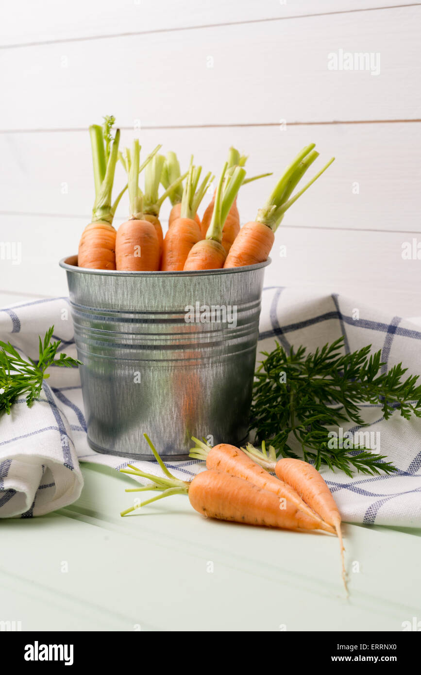 Carrots inside metal bucket on the light green wooden table Stock Photo ...