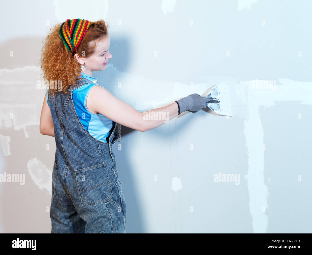 Portrait of a smiling young woman construction worker patching up ...