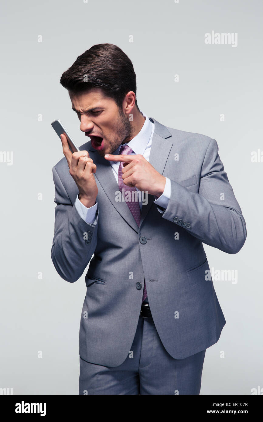 Angry businessman shouting on the phone over gray background Stock ...