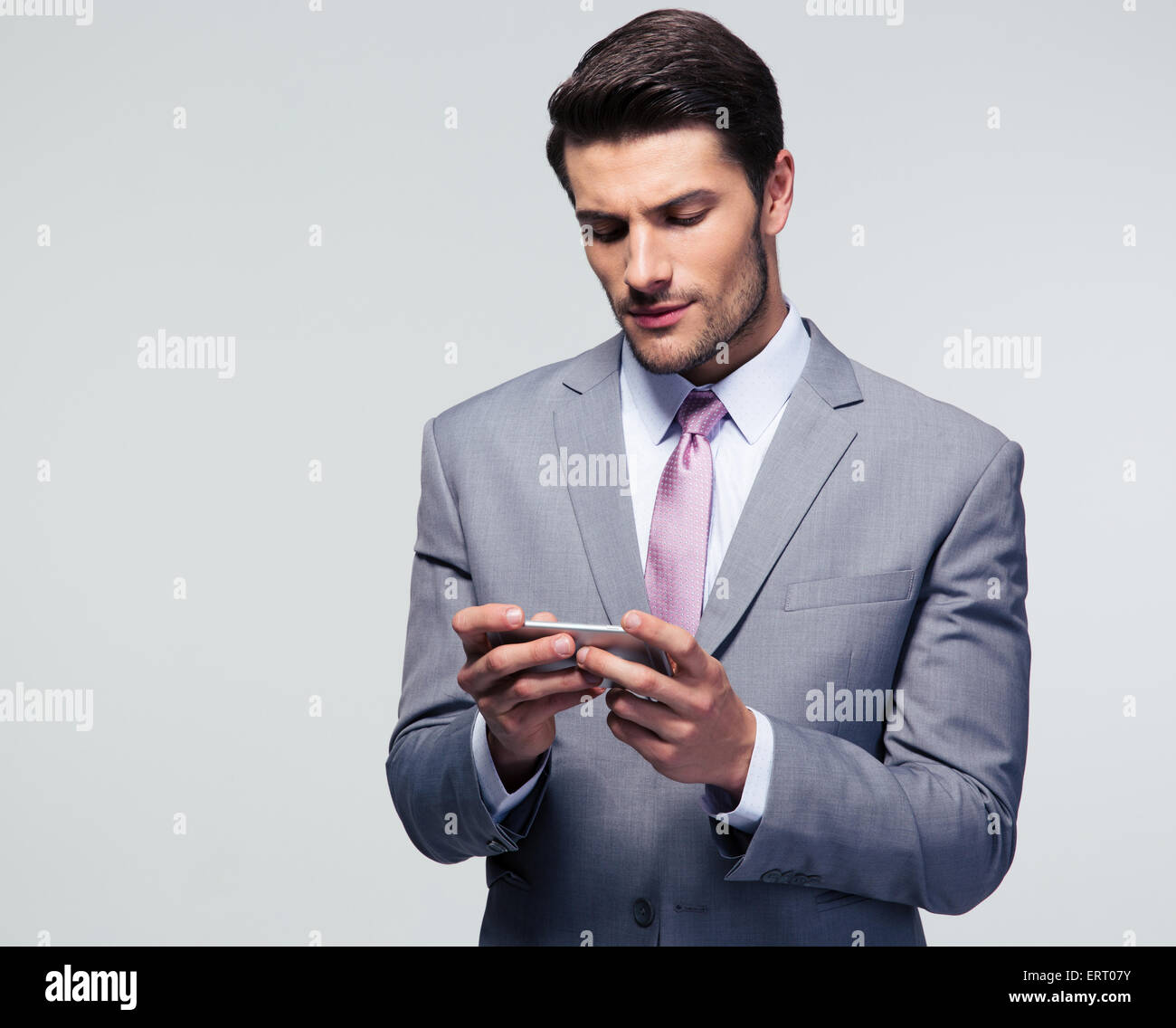 Handsome businessman using smartphone over gray background Stock Photo ...