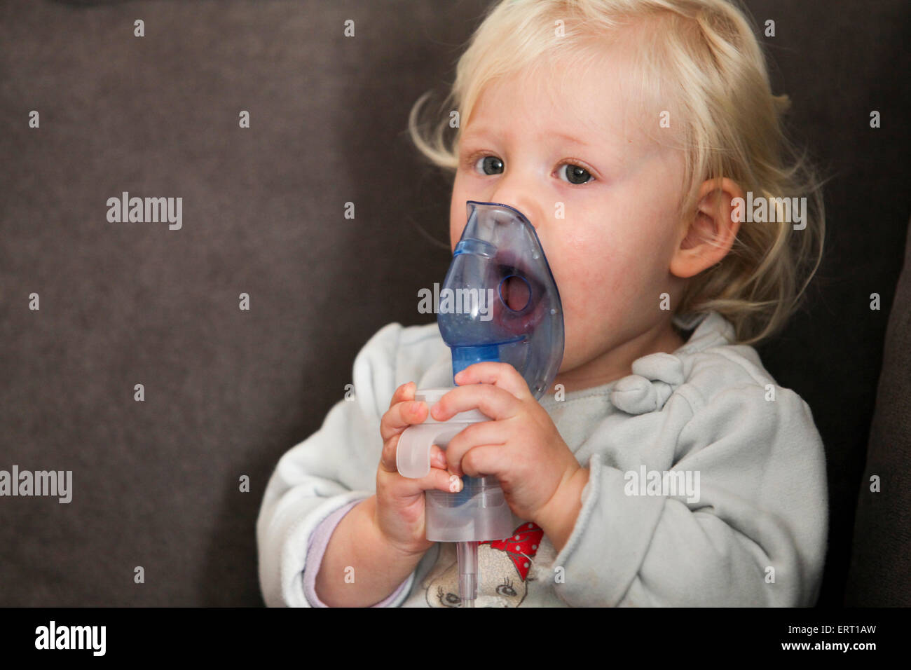 Baby uses an inhalation mask by herself Stock Photo - Alamy