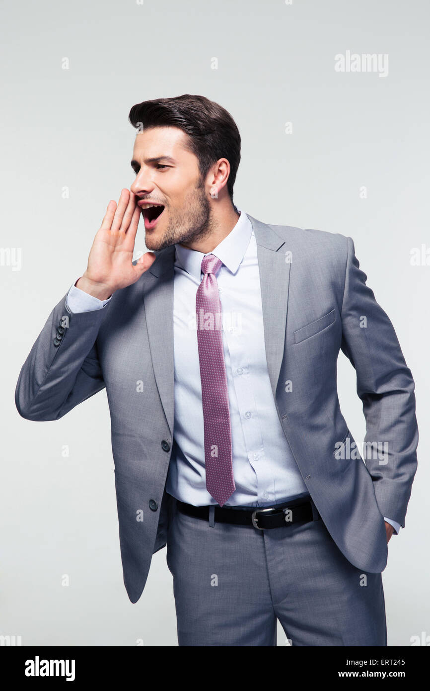 Handsome businessman screaming over gray background Stock Photo - Alamy