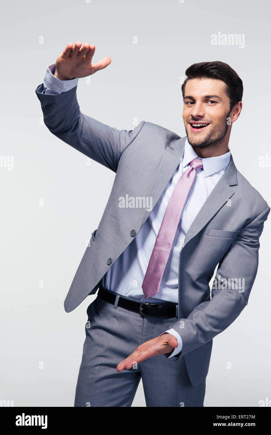 Happy businessman bragging about the size of something over gray ...