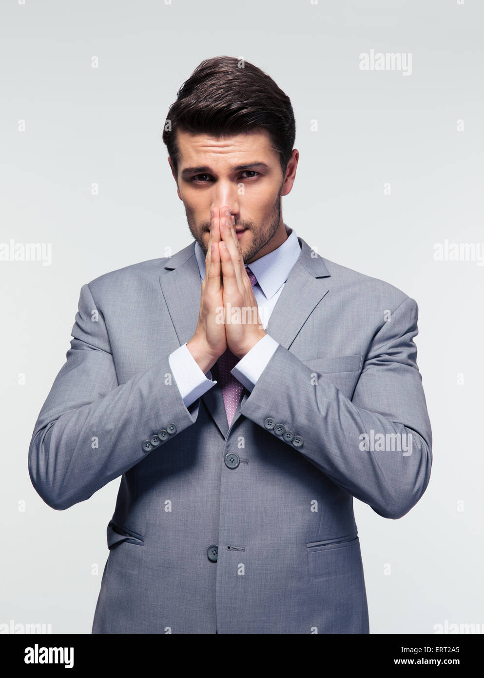 Handsome businessman praying over gray background Stock Photo - Alamy