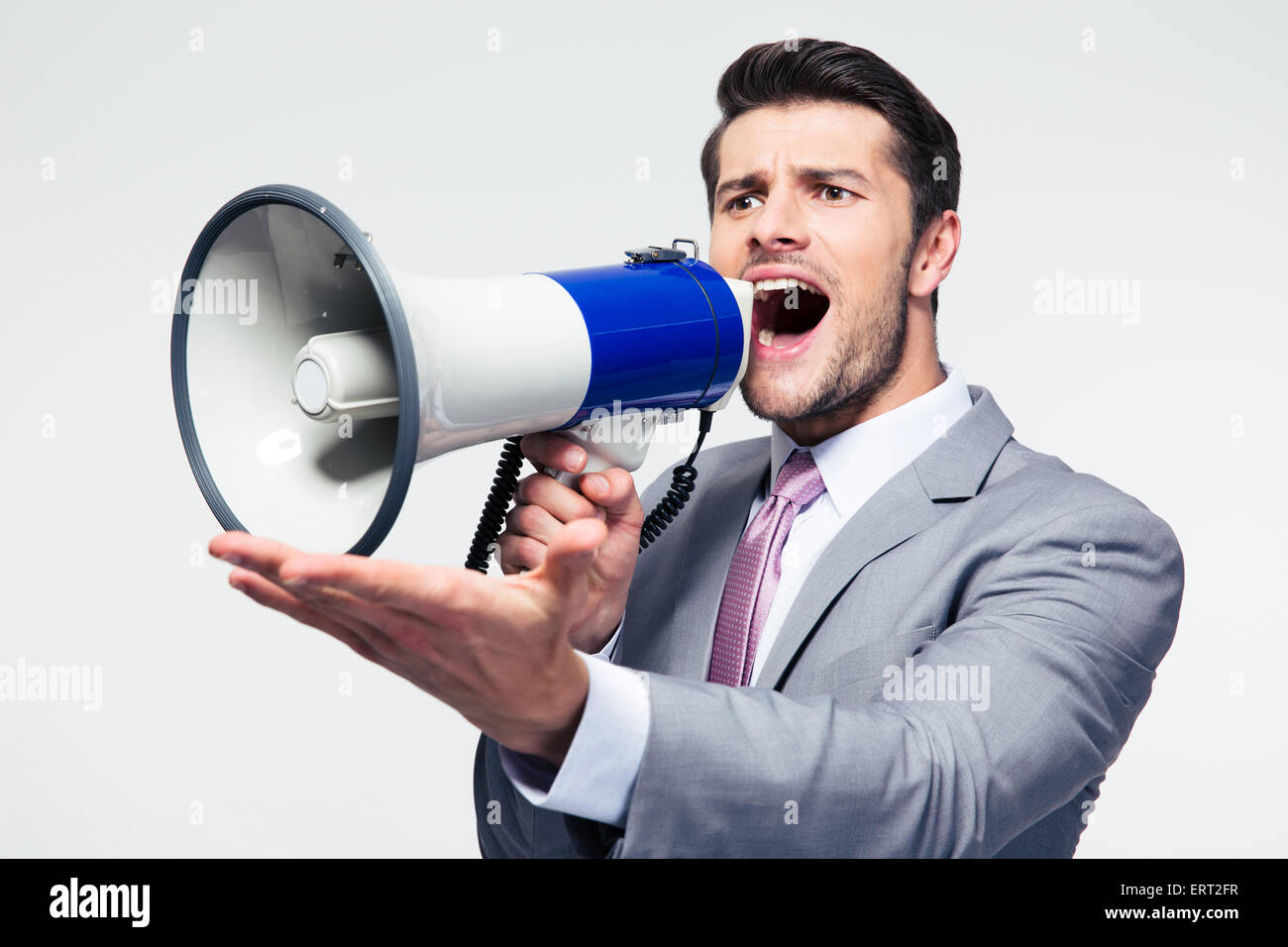 Confident businessman screaming in megaphone over gray background Stock ...