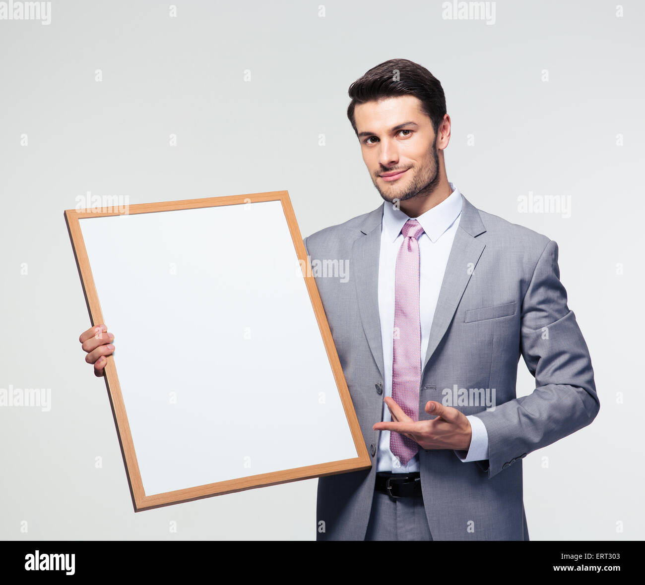 Happy businessman presenting blank board over gray background. Looking ...