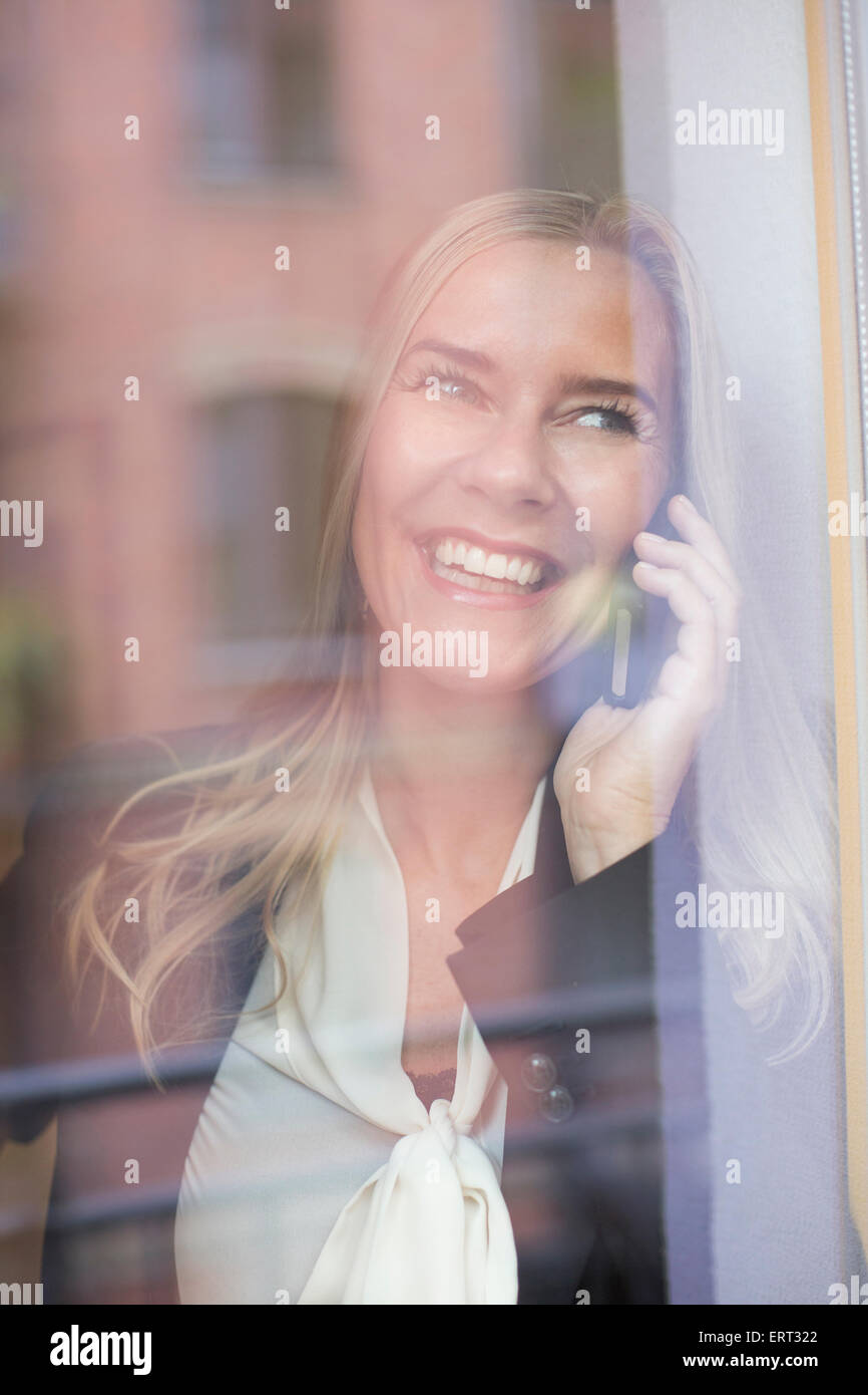 blond woman looking out of window and talking on the phone Stock Photo ...