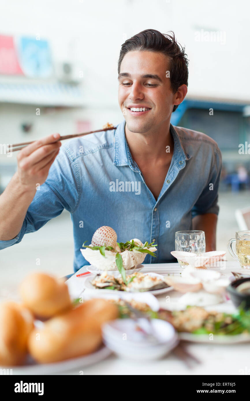 Tourist man eating asian food street local cafe, smile Stock Photo - Alamy