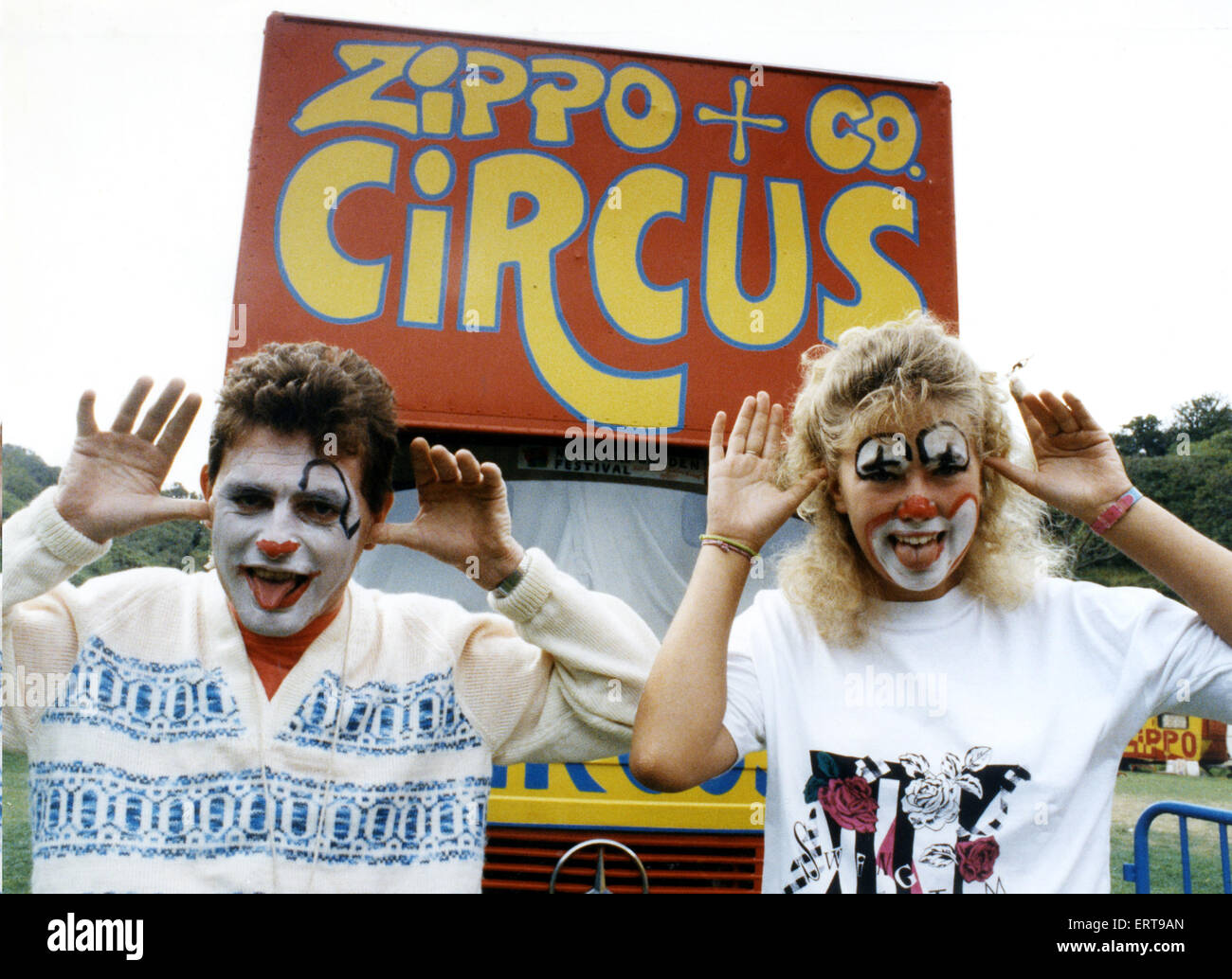 Two people with their faces painted like clowns, pulling funny faces ...