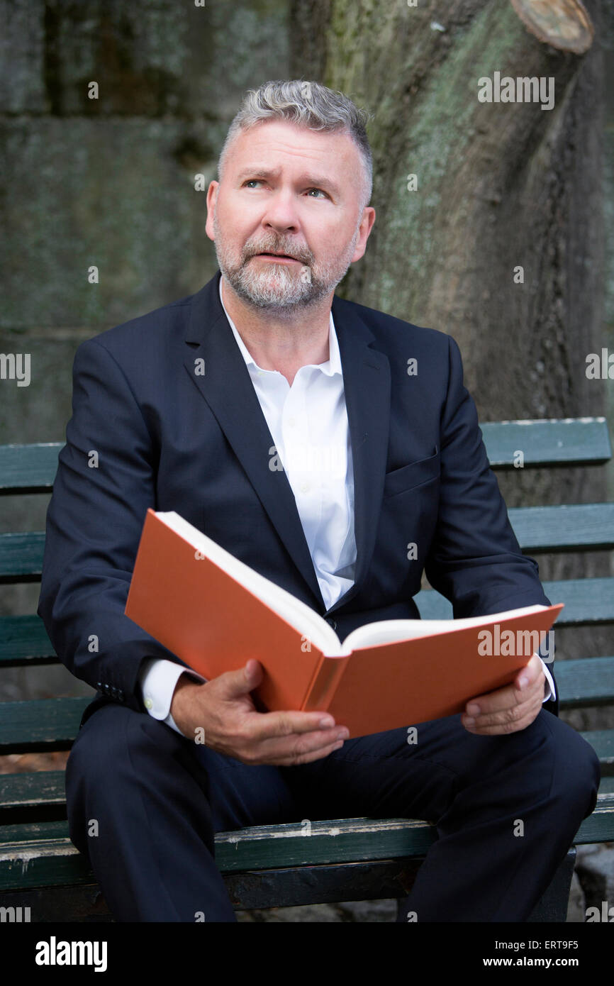 businessman sitting on a bench with a book Stock Photo - Alamy