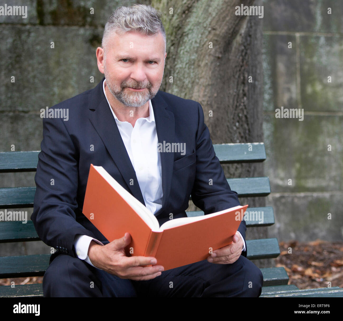 businessman sitting on a bench with a book Stock Photo - Alamy