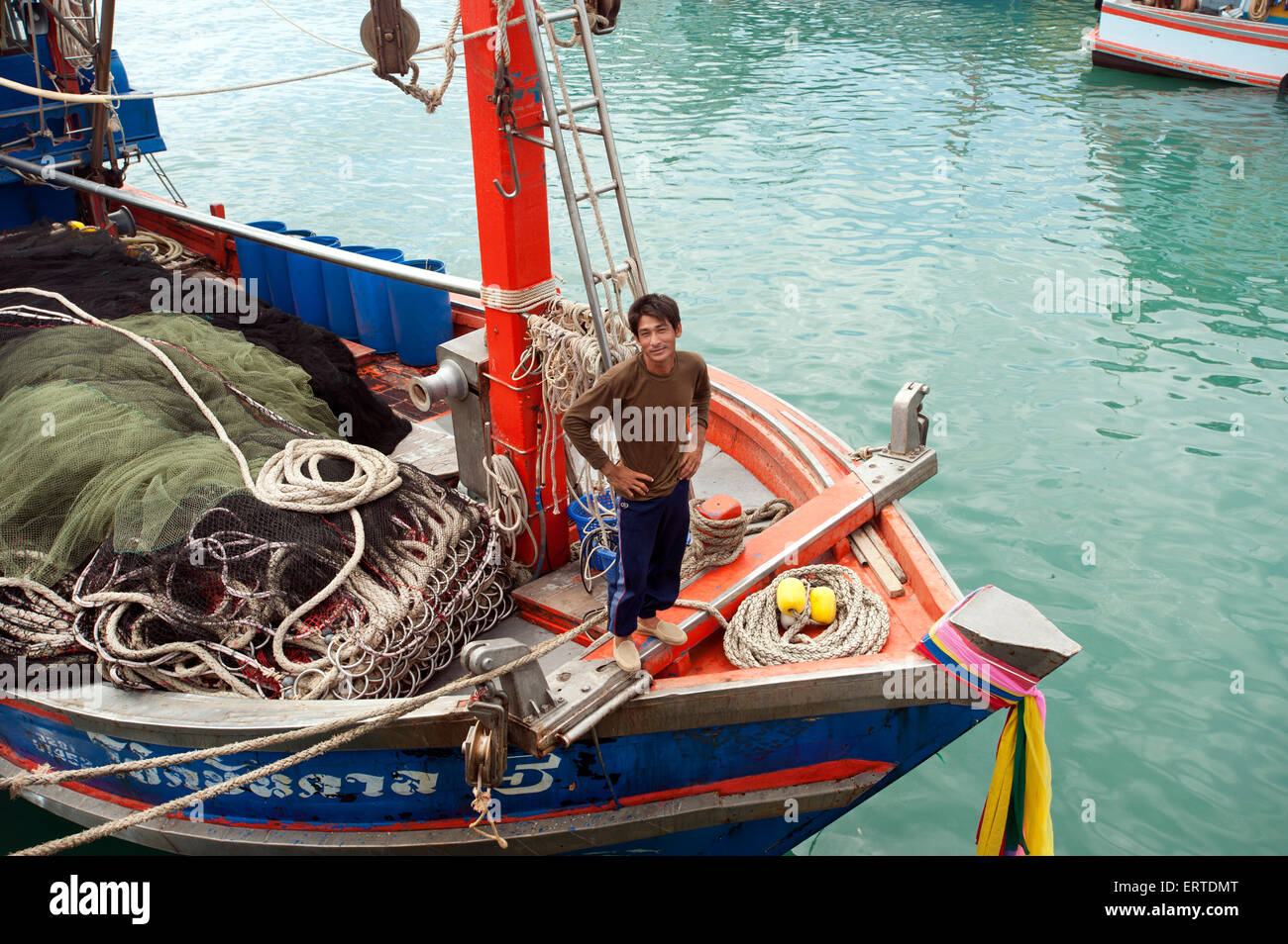 One Thai fisherman looks up from the bow of his fishing trawler moored ...