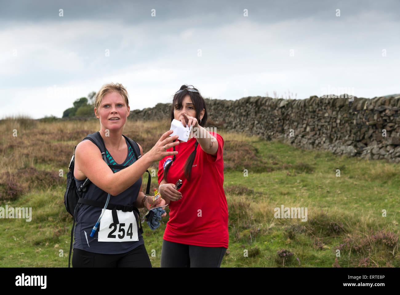 Woman pointing direction to long distance runner in the Peak District ...