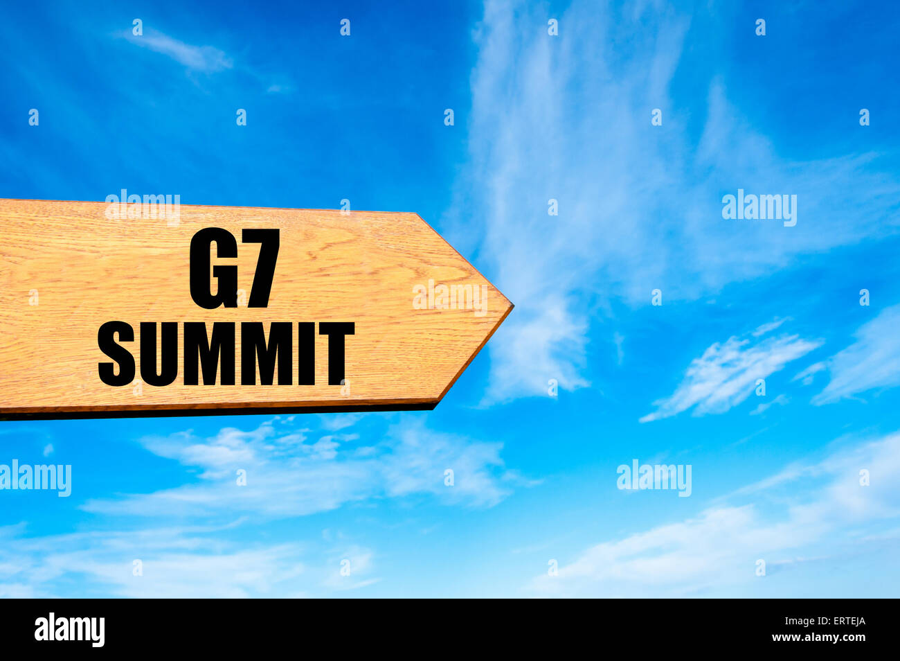 Wooden arrow sign pointing destination G7 SUMMIT against clear blue sky ...