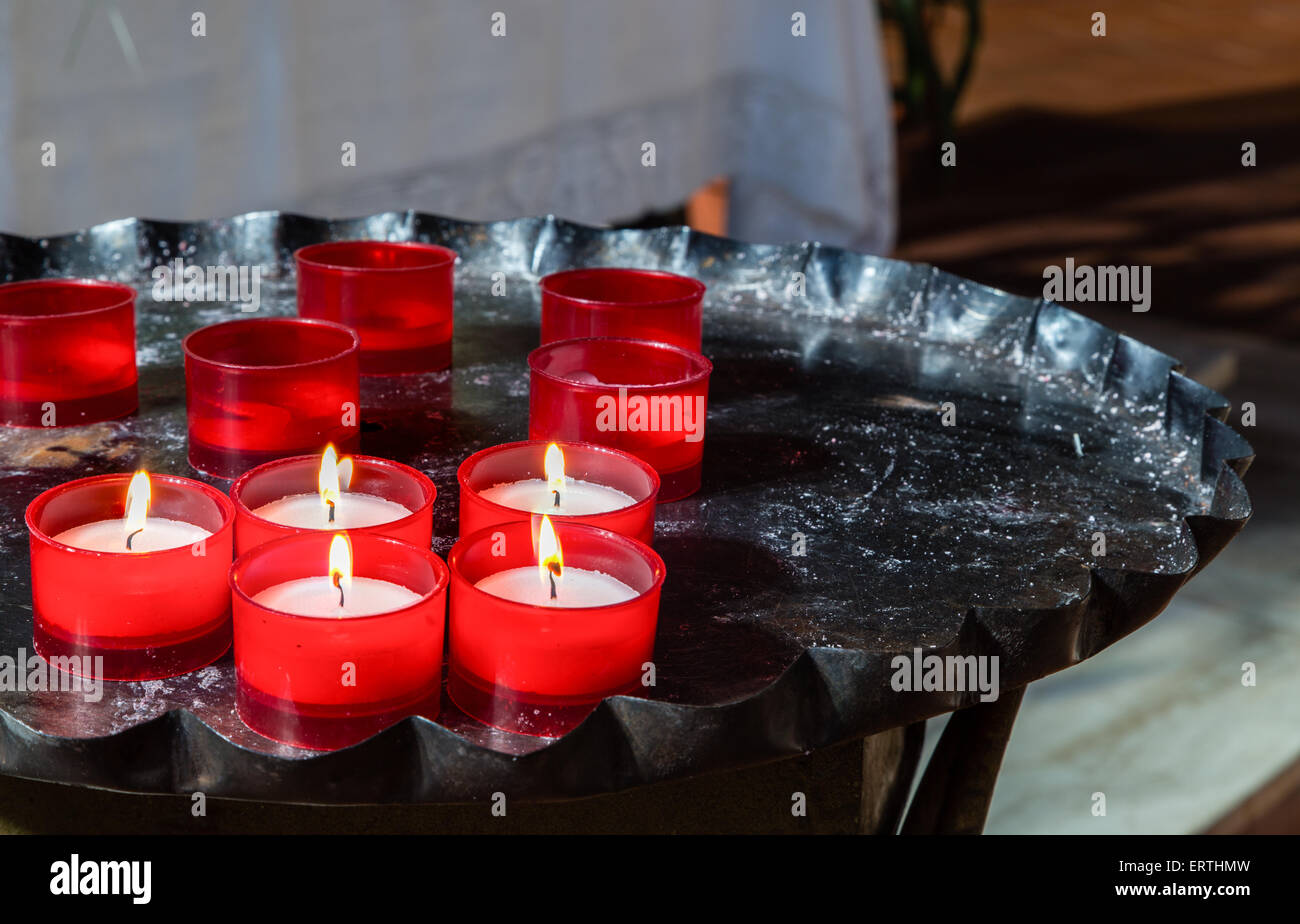 red votive candles arranged on old black iron candlestick, some still ...