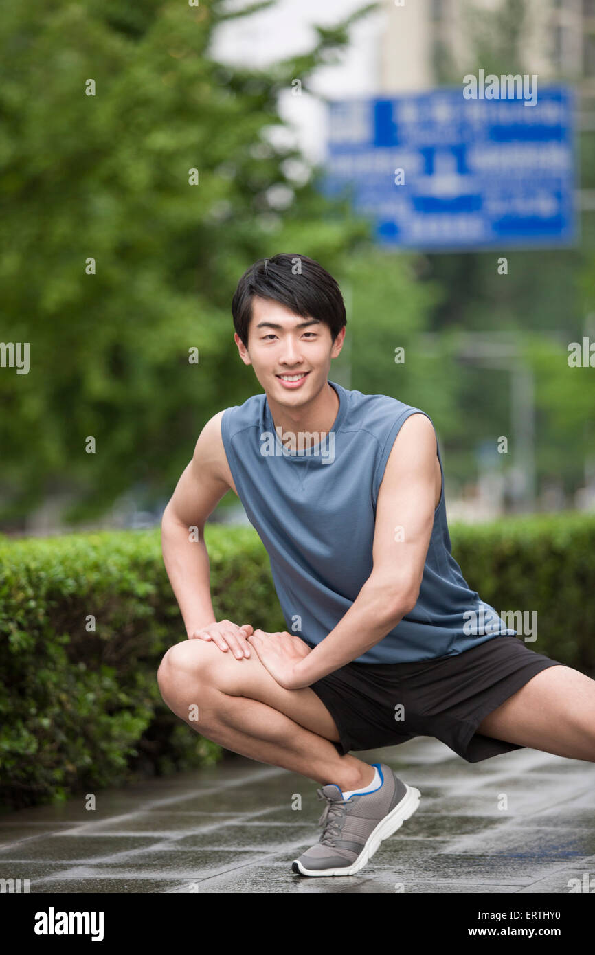 Young man stretching leg outside Stock Photo - Alamy