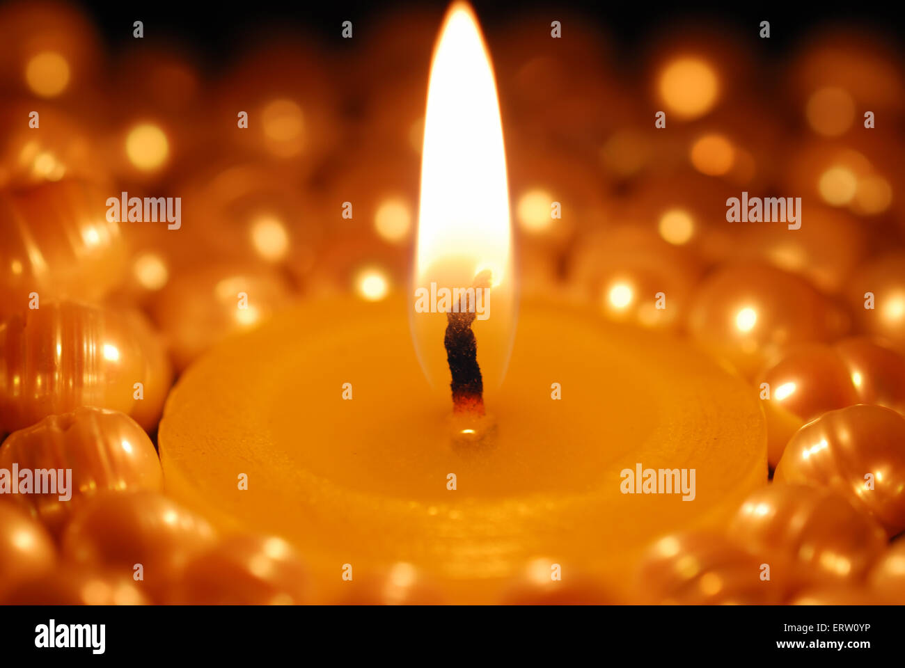 Burning candle in the centre of pearls on dark Stock Photo - Alamy