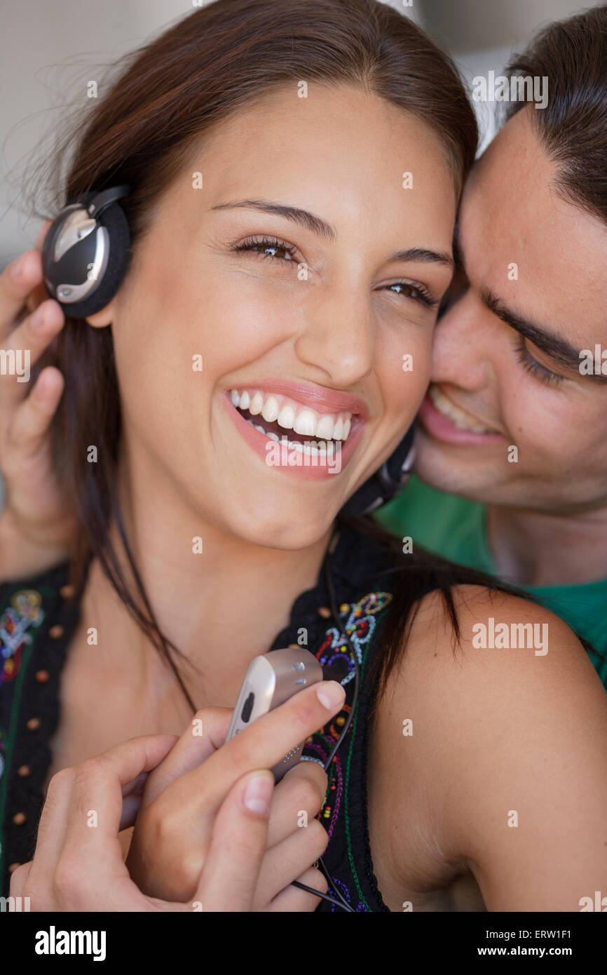 Couple with headphones, man whispering into womans ear Stock Photo - Alamy