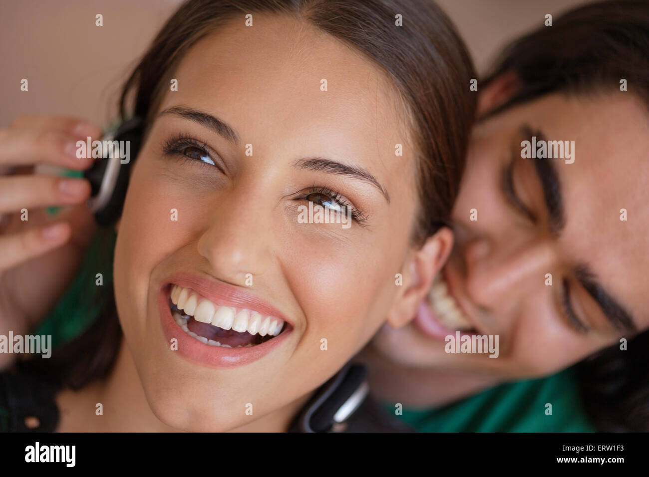 Couple with headphones, man whispering into womans ear Stock Photo - Alamy