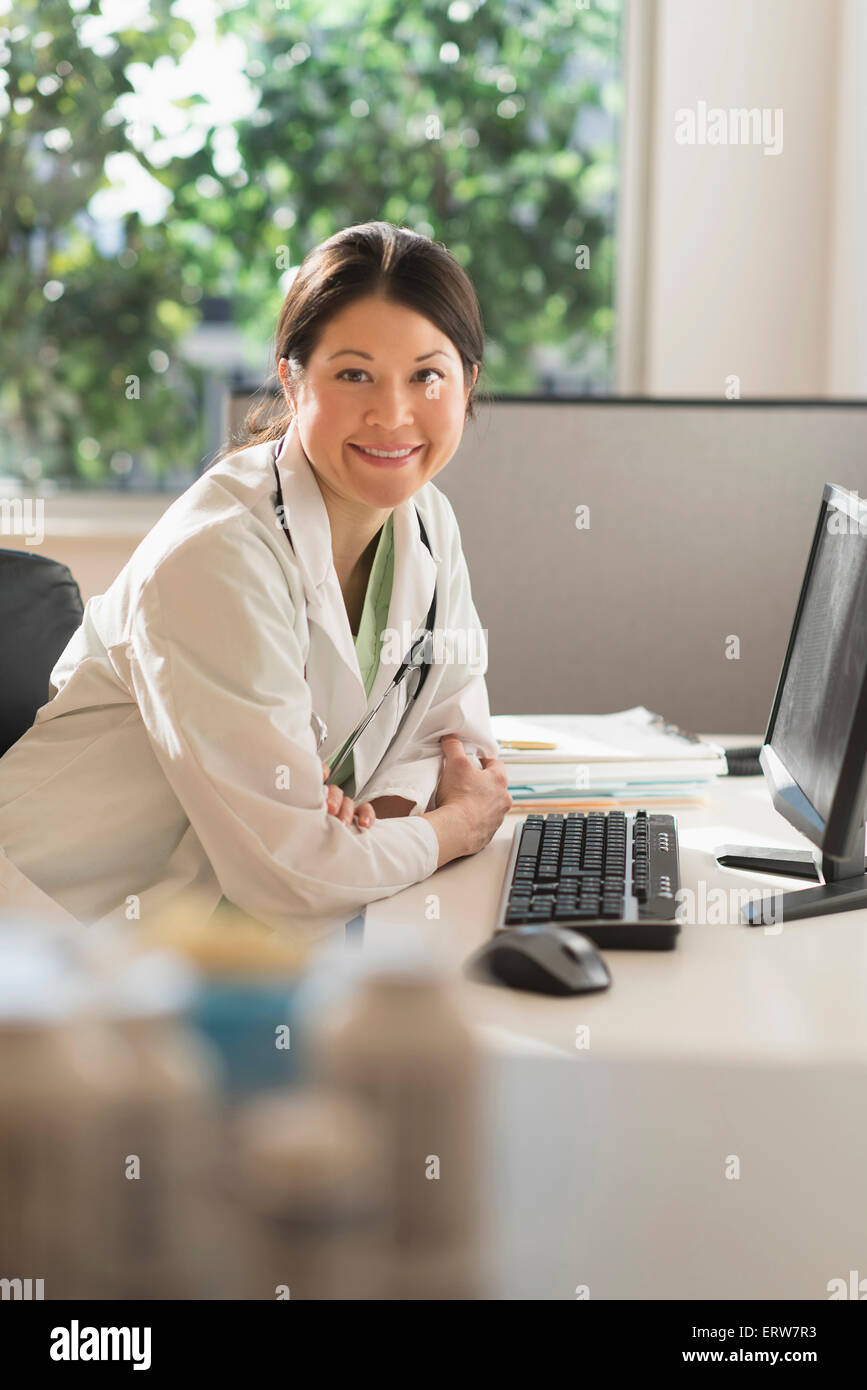 Mixed race doctor smiling at computer in hospital Stock Photo - Alamy