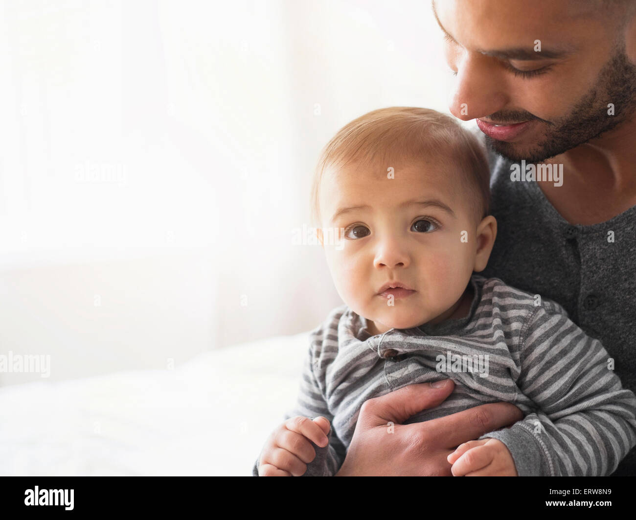 Smiling father holding baby son on bed Stock Photo - Alamy