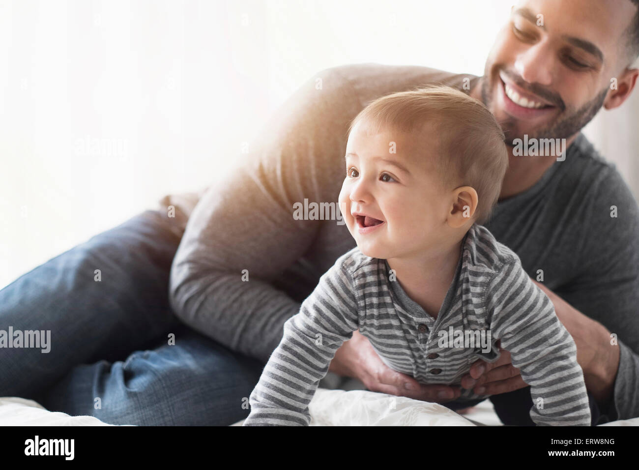 Smiling father playing with baby son on bed Stock Photo - Alamy