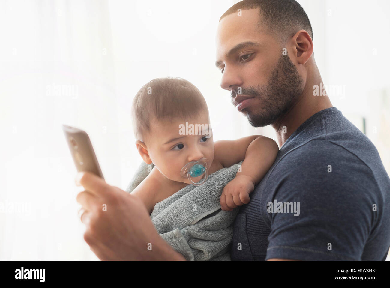 Father holding baby son and using cell phone Stock Photo - Alamy