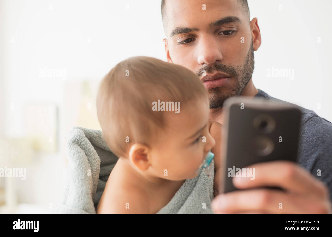 Father holding baby son and using cell phone Stock Photo - Alamy