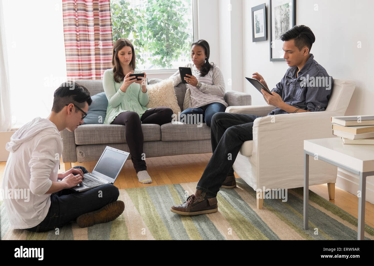 Friends using technology in living room Stock Photo - Alamy