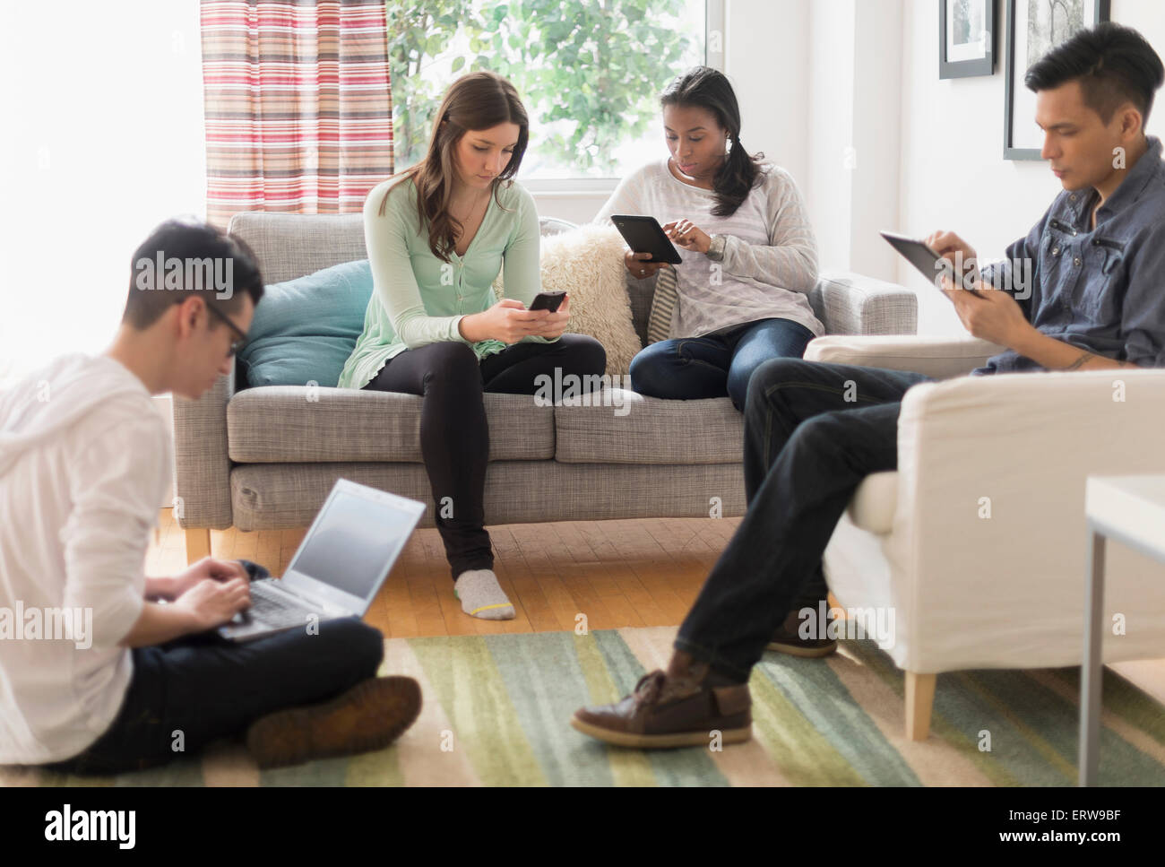 Friends using technology in living room Stock Photo - Alamy